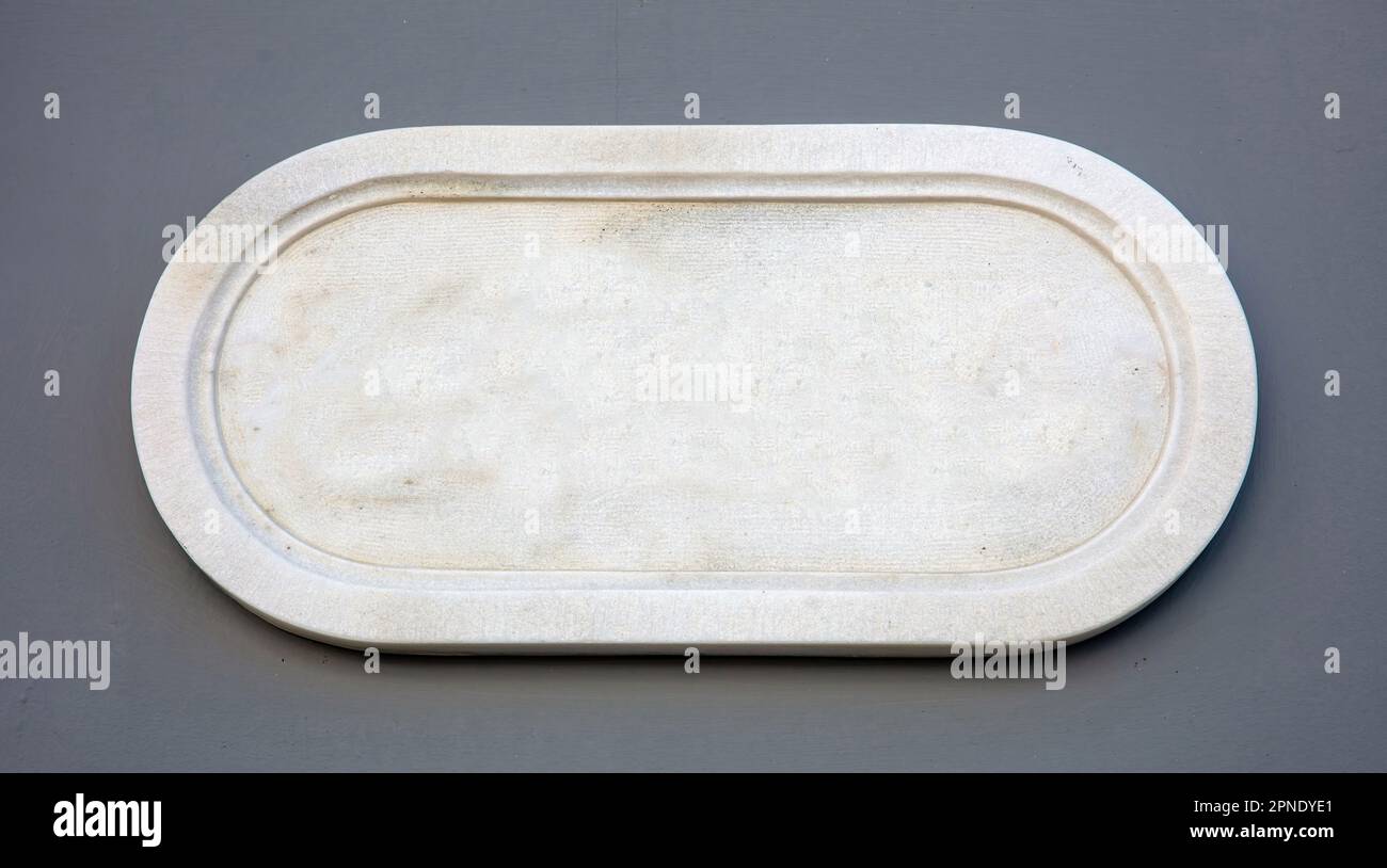 Marble sign blank on grey wall. White empty label, oval shape, copy ...