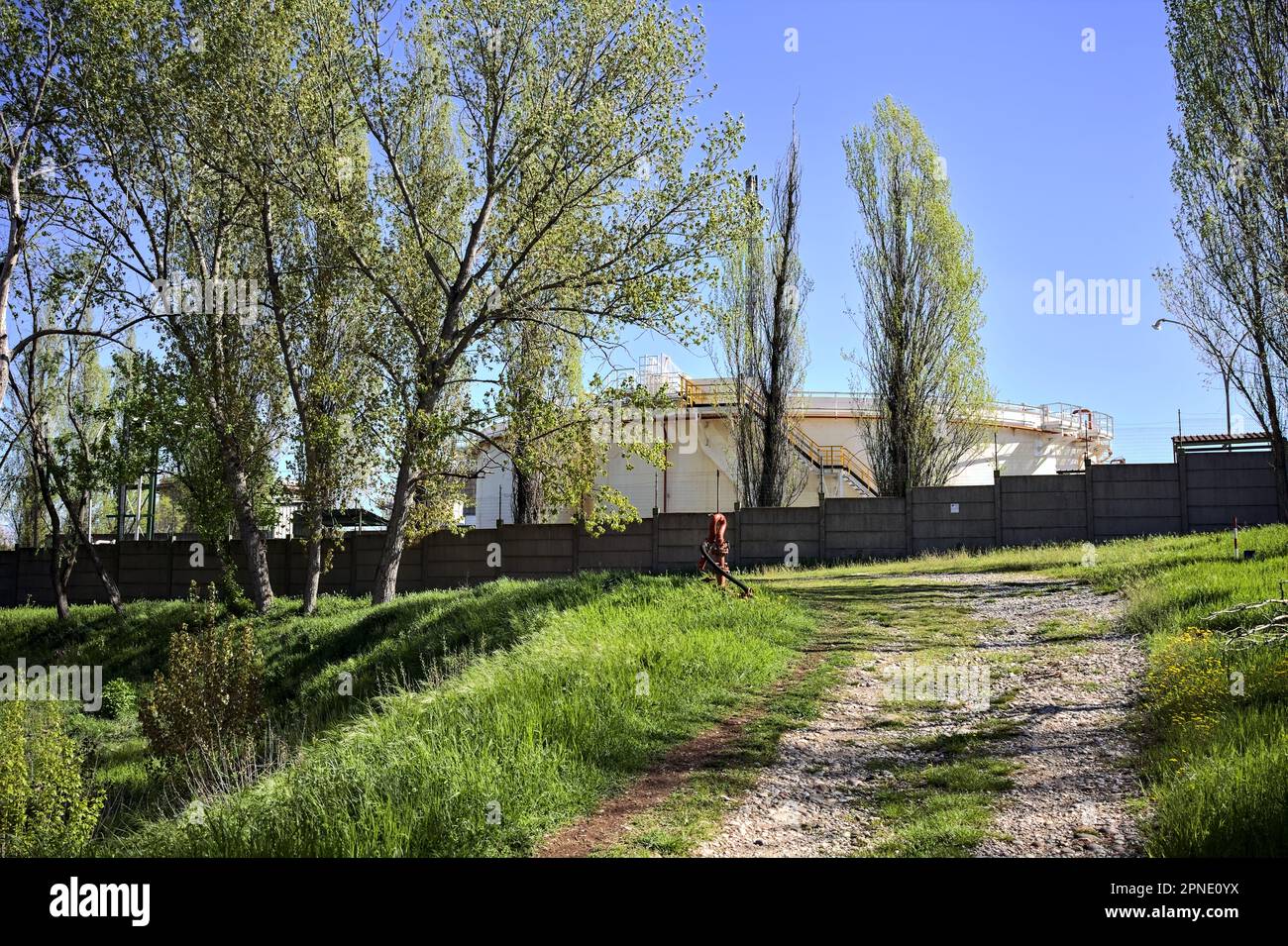 Path on an embankment next to a boundary wall of an industrial complex ...