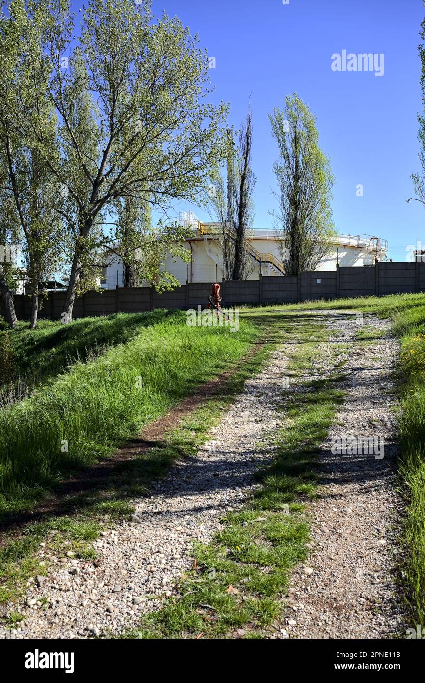 Path on an embankment next to a boundary wall of an industrial complex ...