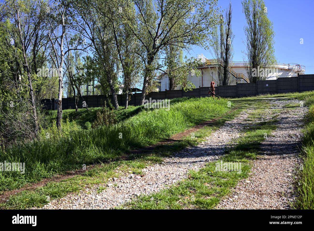 Path on an embankment next to a boundary wall of an industrial complex ...