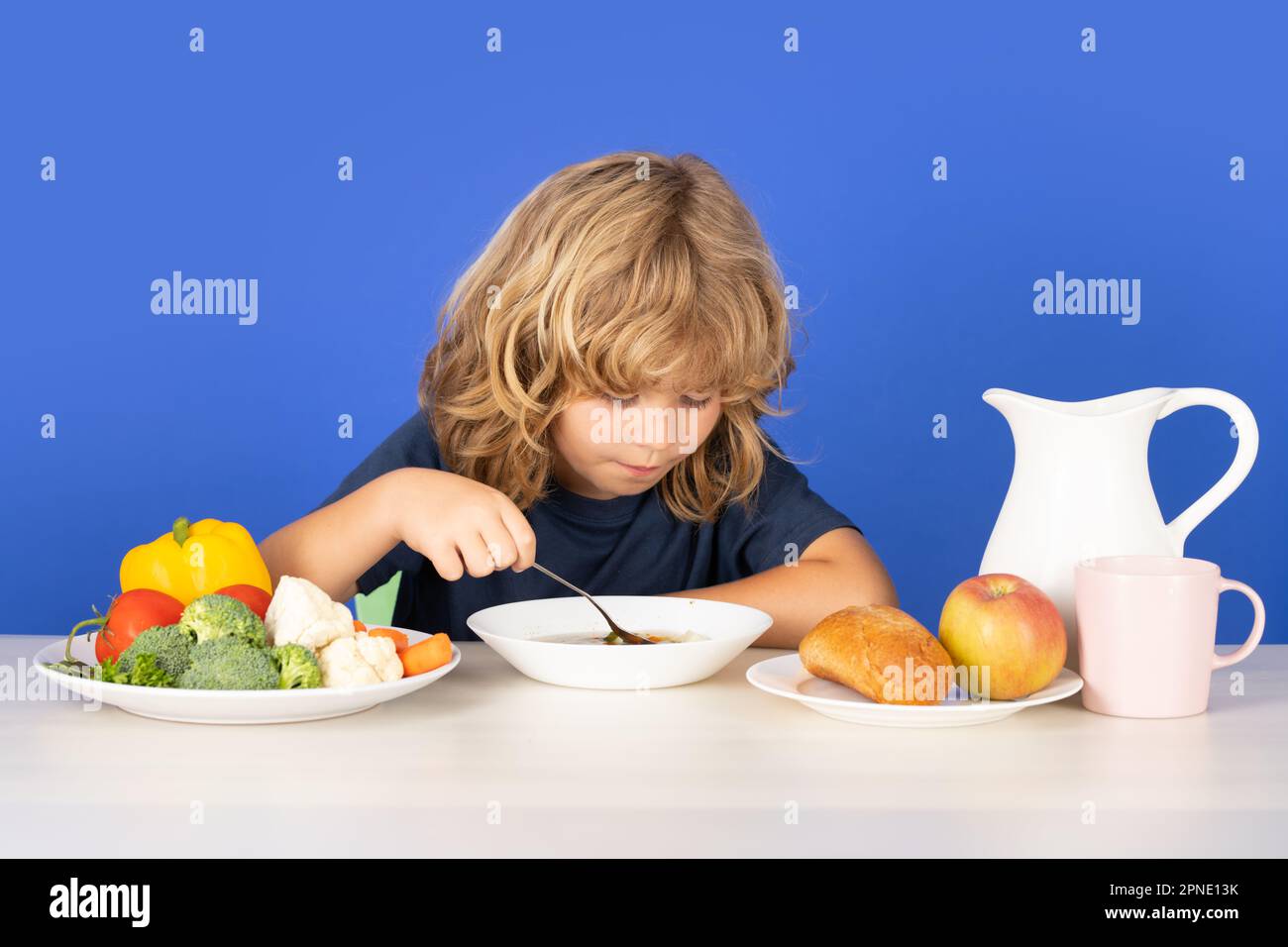 Child eating soup. Adorable little boy eating vegetable soup. Cute kid ...