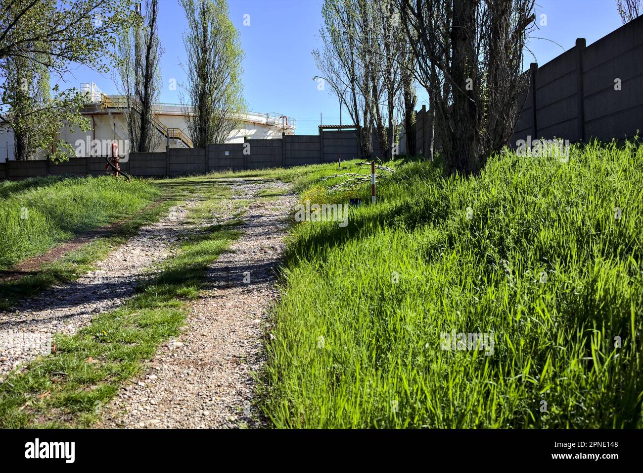 Path on an embankment next to a boundary wall of an industrial complex ...