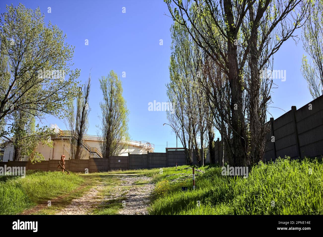 Path on an embankment next to a boundary wall of an industrial complex ...