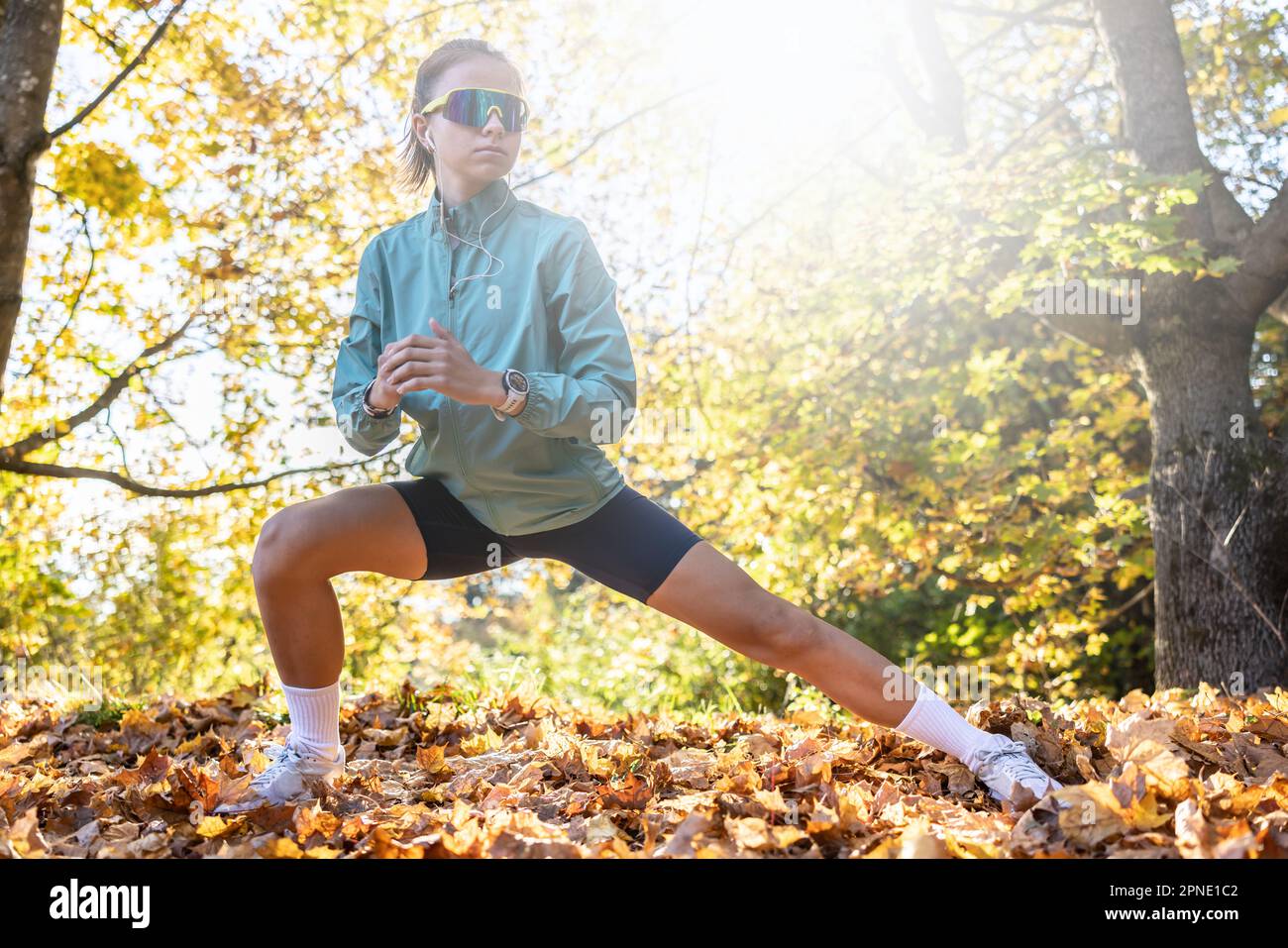 Young woman stretches his leg on a autumn day outdoors, wearing watches ...
