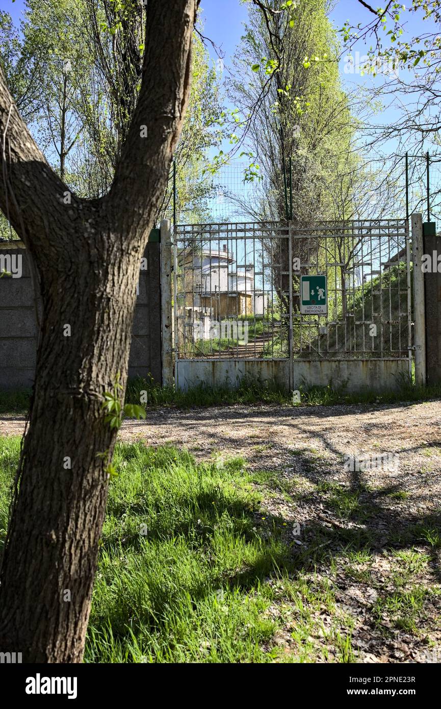 Gate in a concrete boundary wall of a factory by the edge of a path in ...