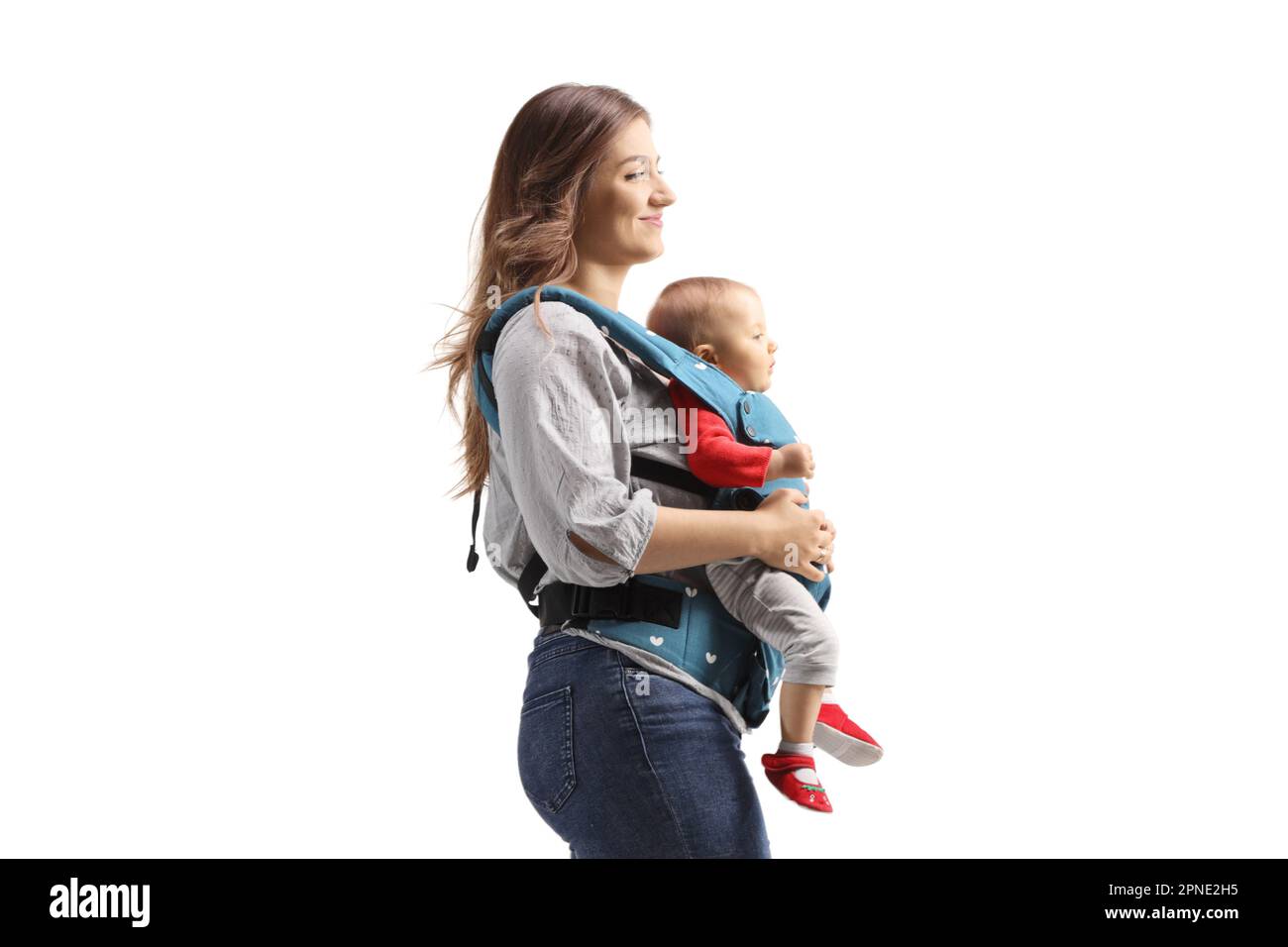 Profile shot of a mother walking and carrying a baby in a carrier ...