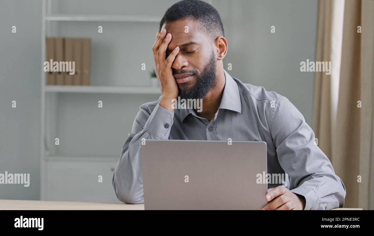 Sad upset failure ethnic bearded office worker online problem at work African American ...