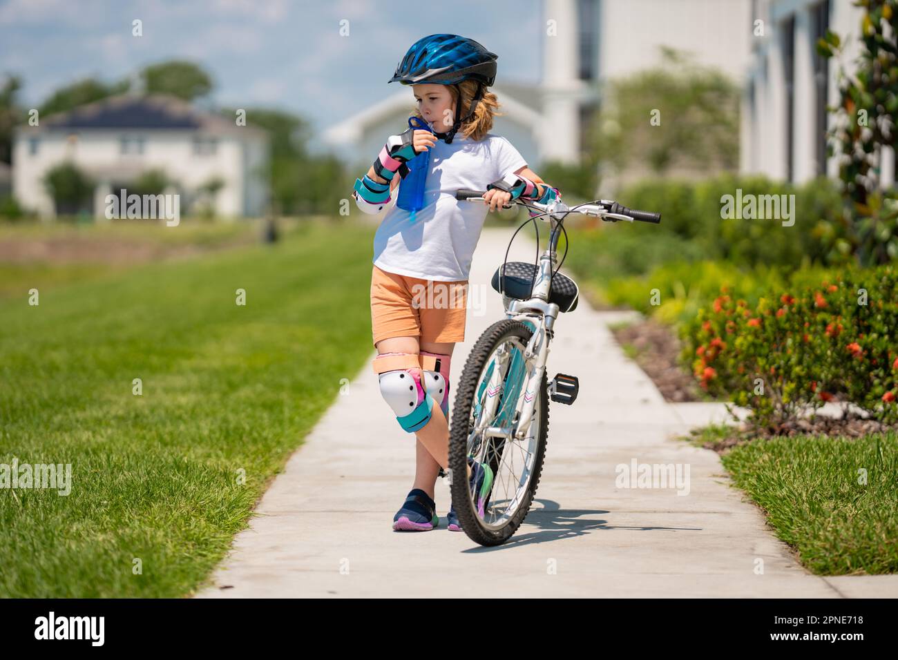 Kid riding bike in a helmet. Child with a childs bike and in protective ...