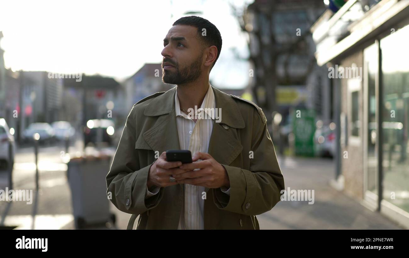 One Arab young man searching for location while walking in city street ...
