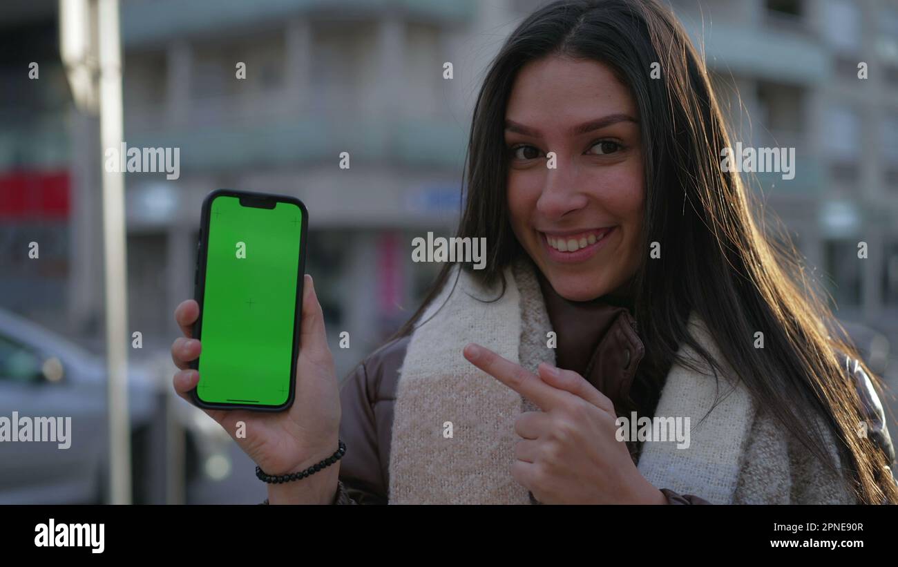 One happy young woman showing phone to camera with chroma key ...