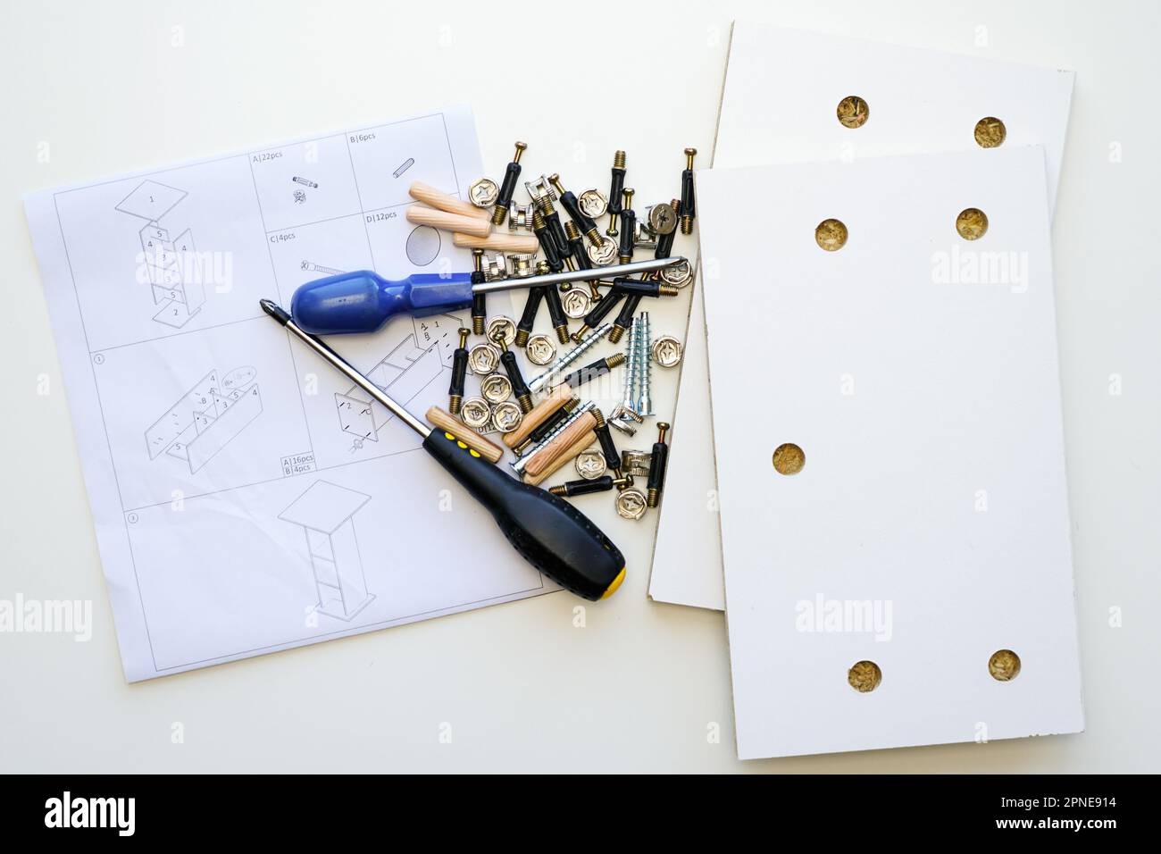 A pile of a various assembly fittings on a white laminated chipboard ...