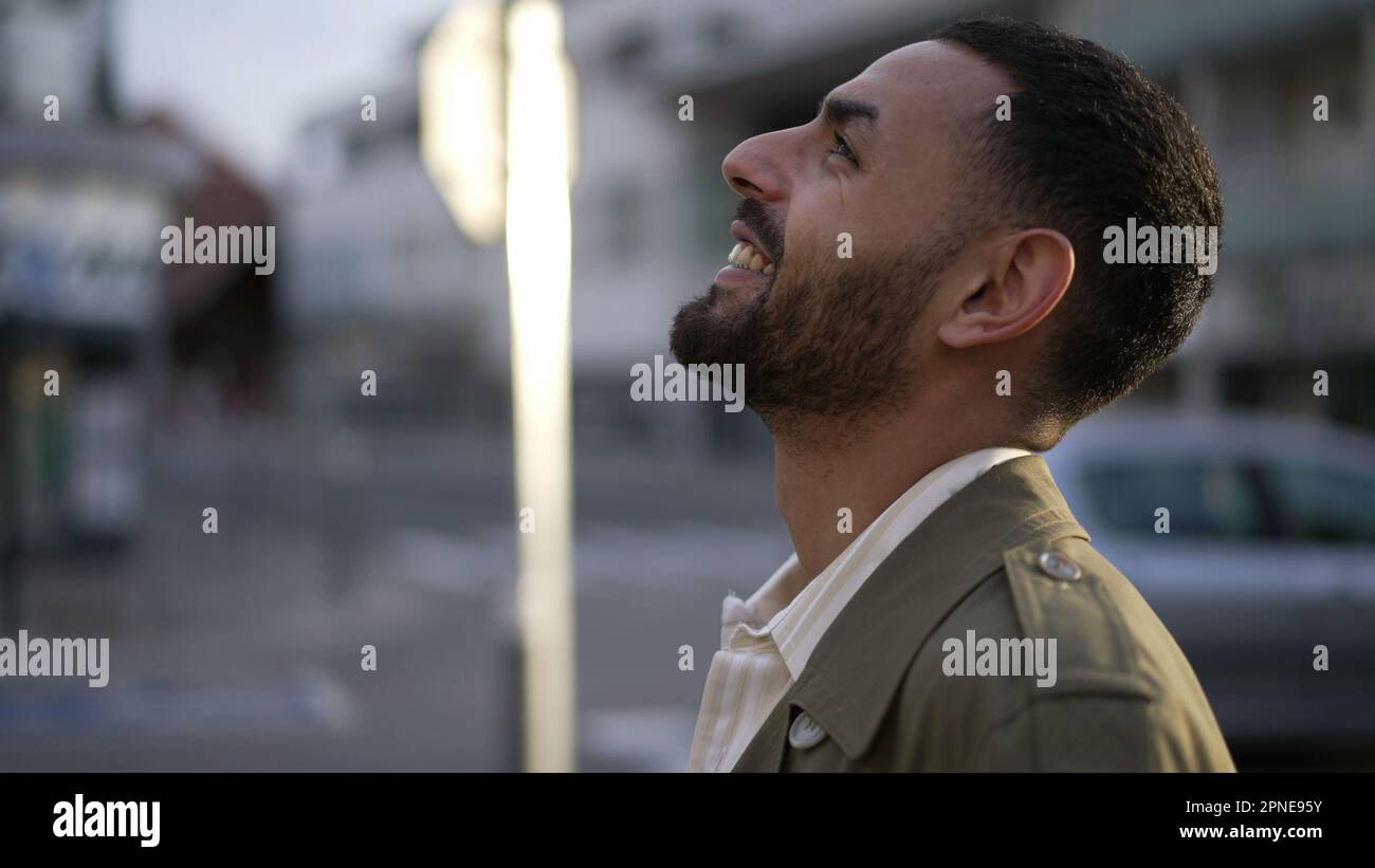 One happy Middle Eastern Man stands in Urban setting looking at sky ...