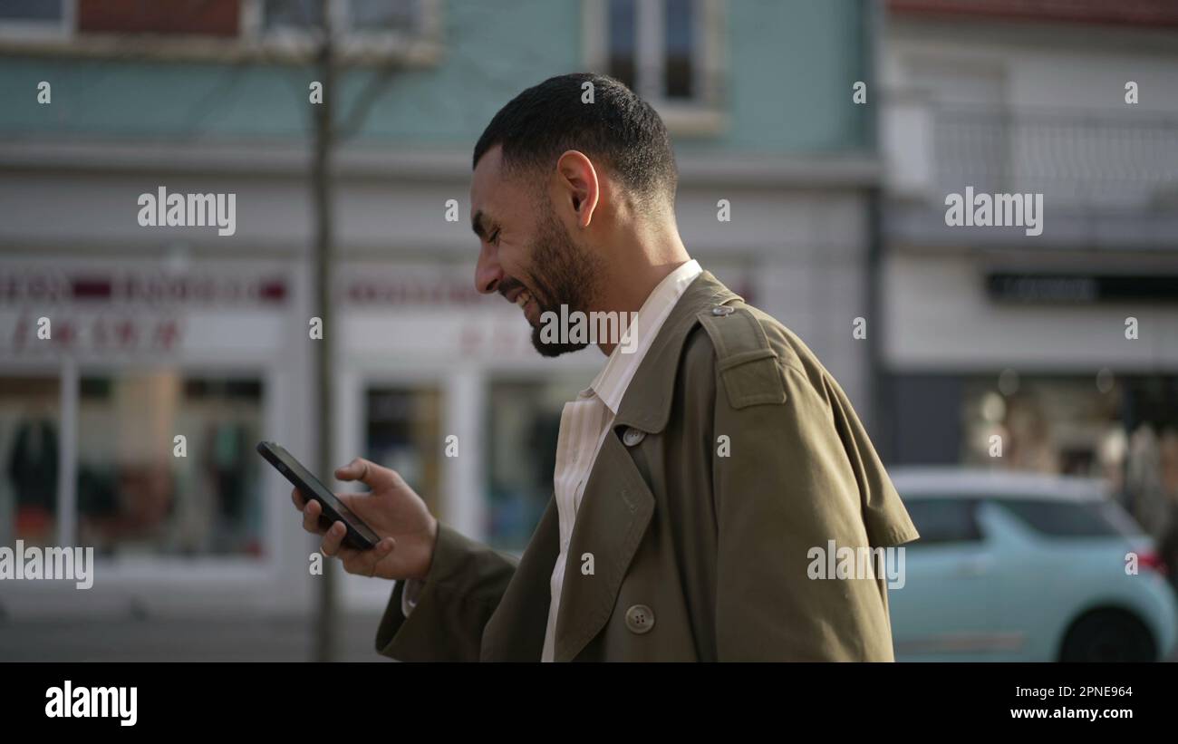 One Happy Middle Eastern man walking in city street holding phone ...