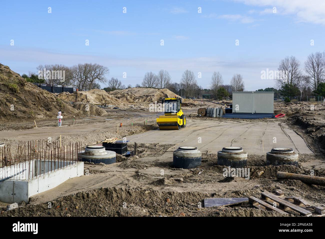 Construction site with underground pipeline wells, road roller and high ...
