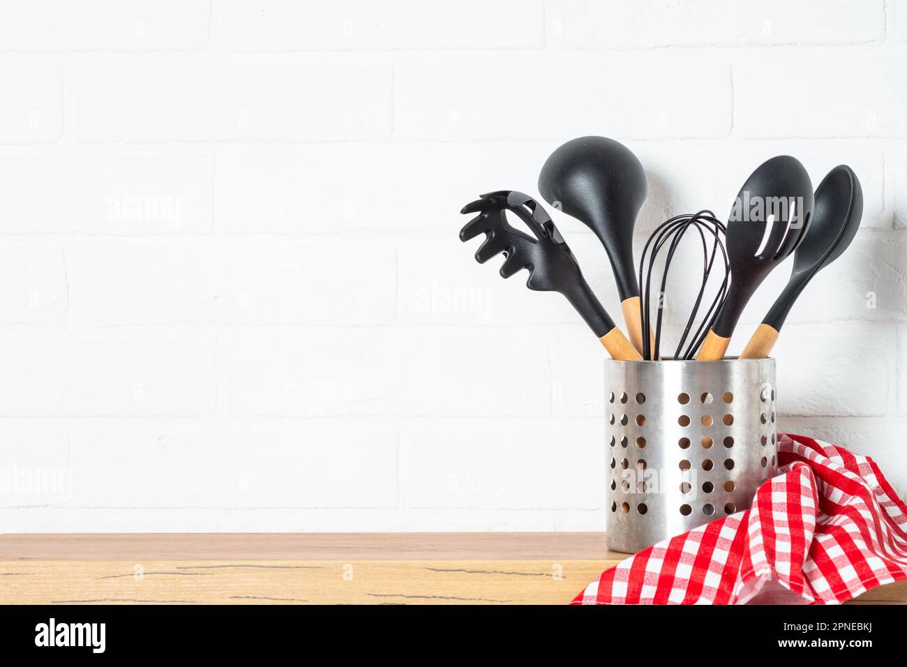Kitchen utensils in container near white wall Stock Photo - Alamy