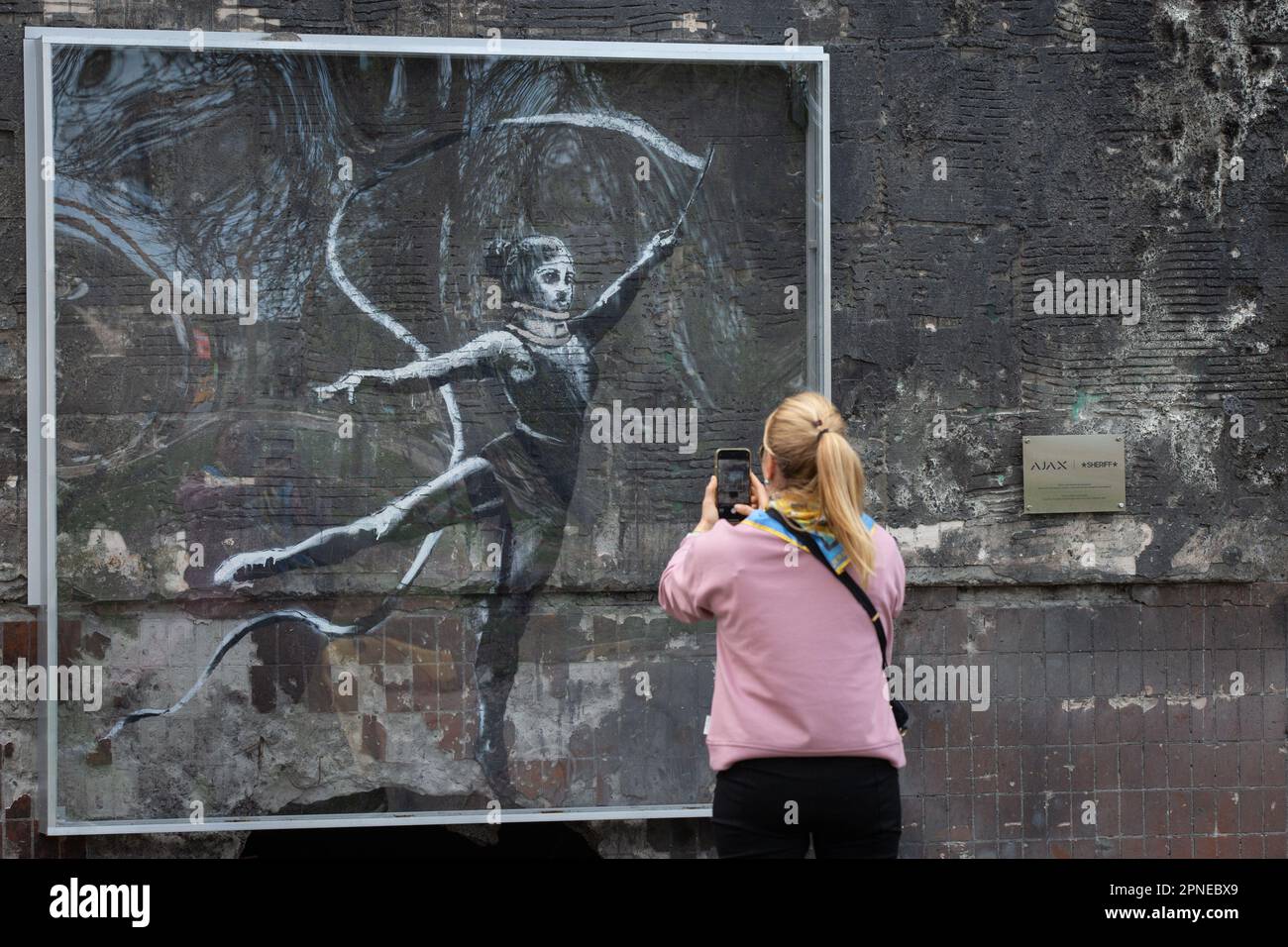 A woman takes pictures of a graffiti by famous British street artist ...