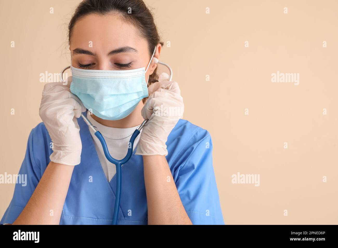 Female medical assistant with stethoscope on beige background Stock ...