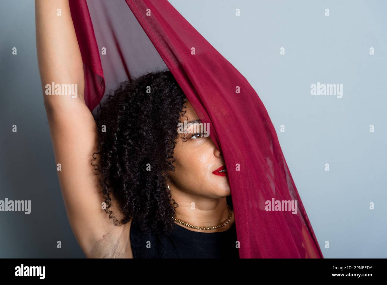 Beautiful young woman with red cloth suspended around her body. studio ...