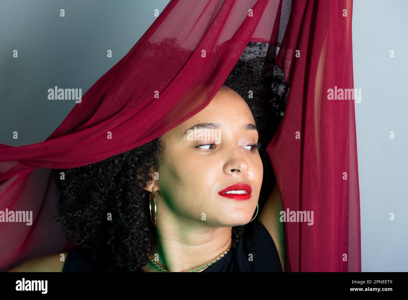 Beautiful young woman with red cloth suspended around her body. studio ...