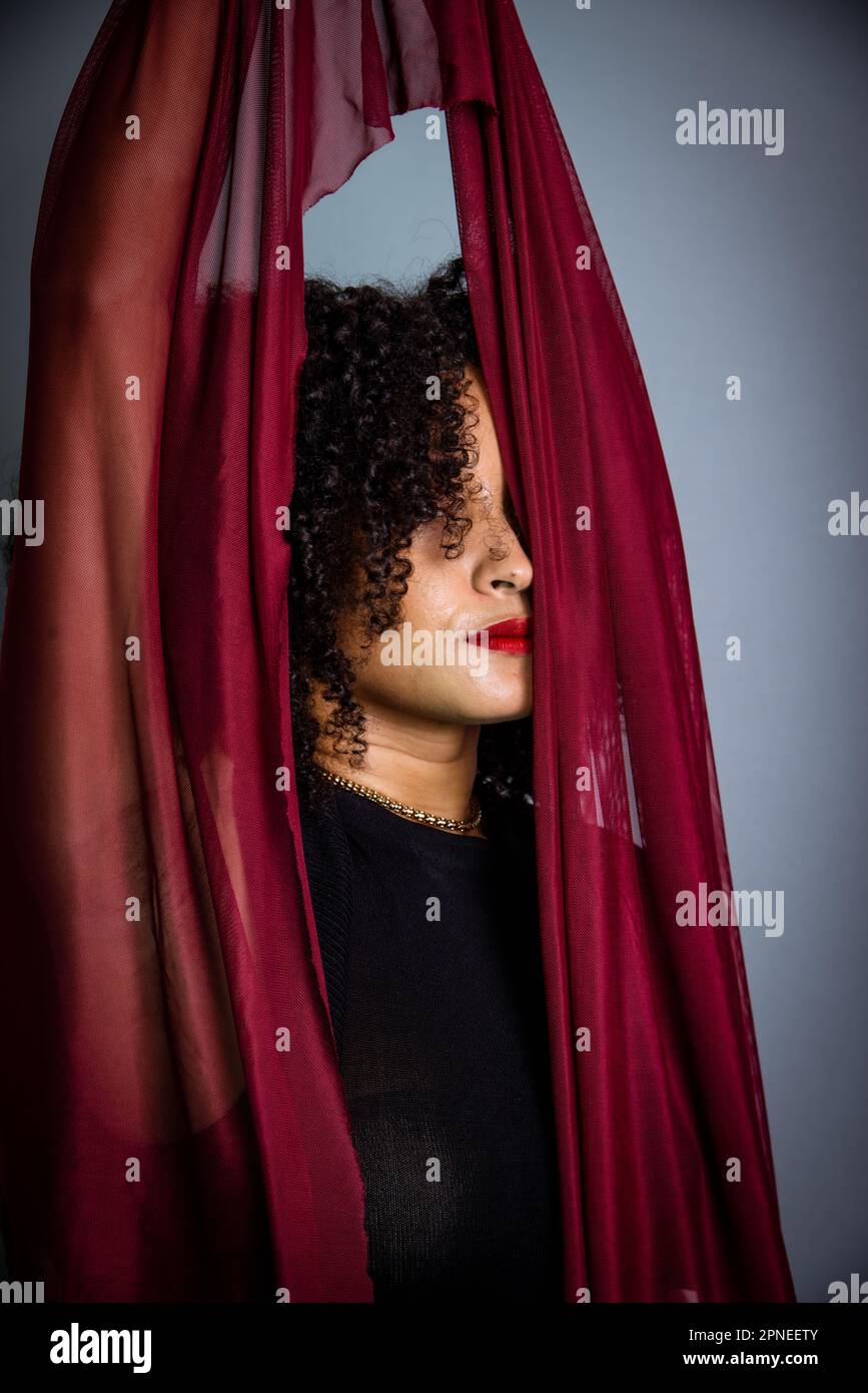 Beautiful young woman with red cloth suspended around her body. studio ...