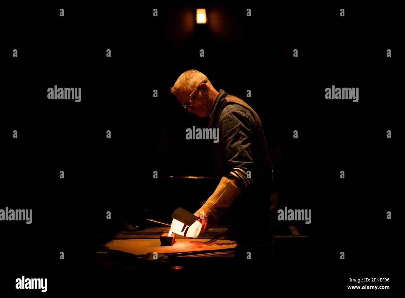 A man pouring smelted gold into an iron mould to create a 24 karat gold ...