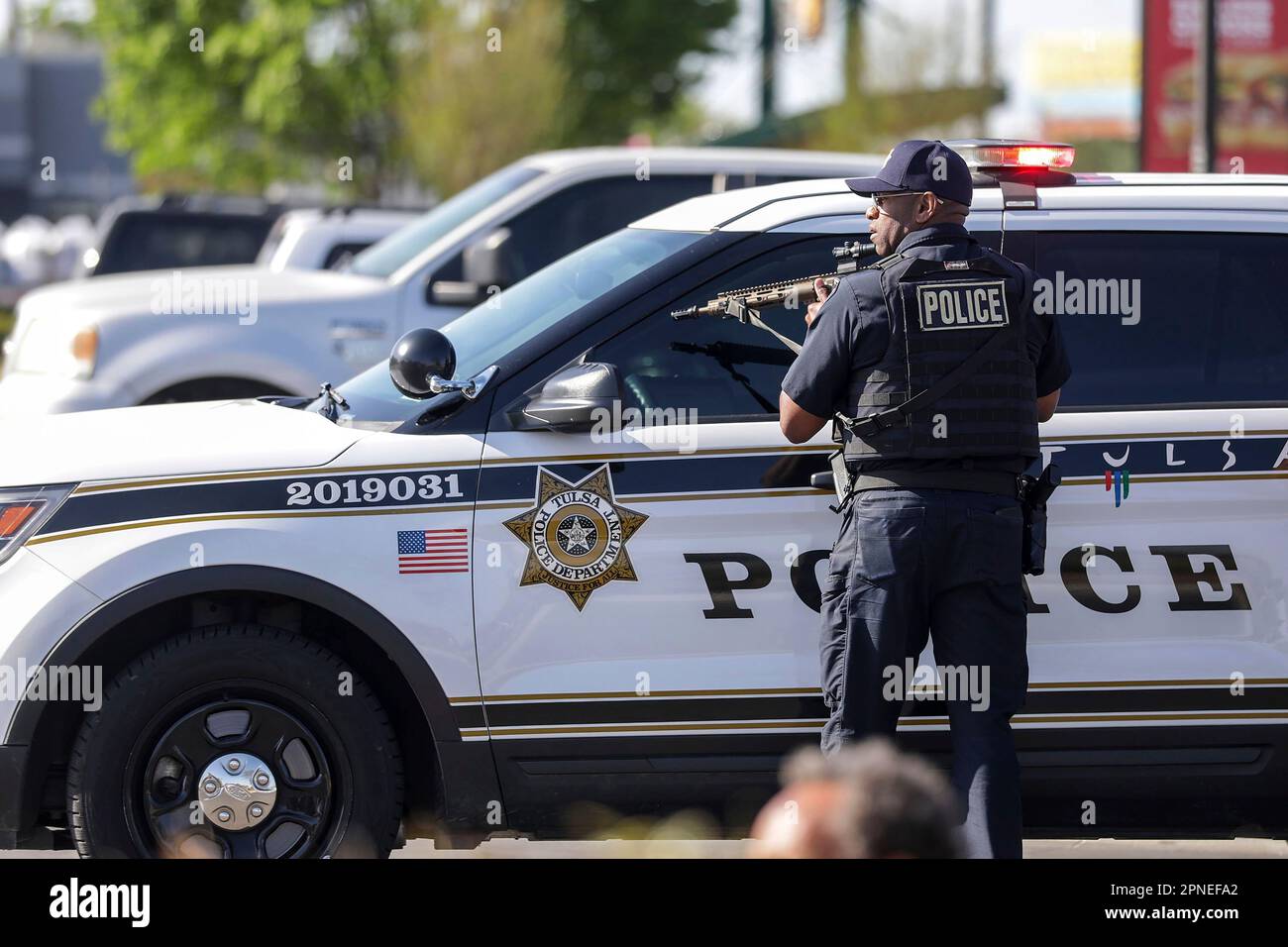 A Tulsa Police officer takes cover behind a car with a weapon at the ...