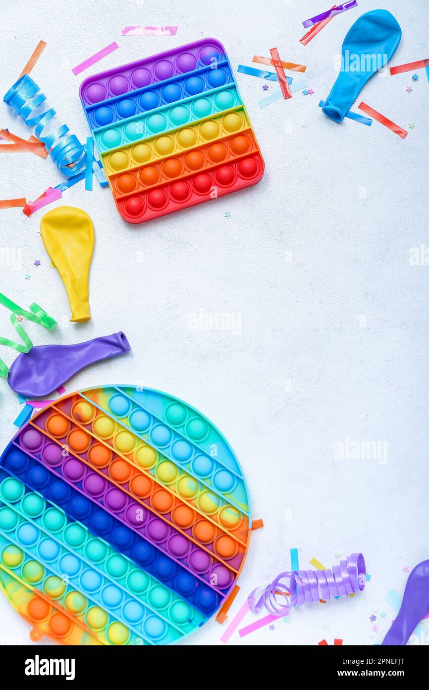 Frame made of pop it toys, balloons and confetti on white background ...