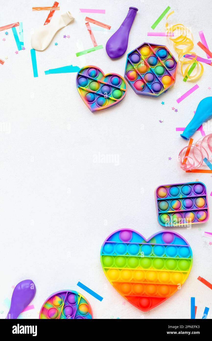 Frame made of pop it toys, balloons and confetti on white background ...