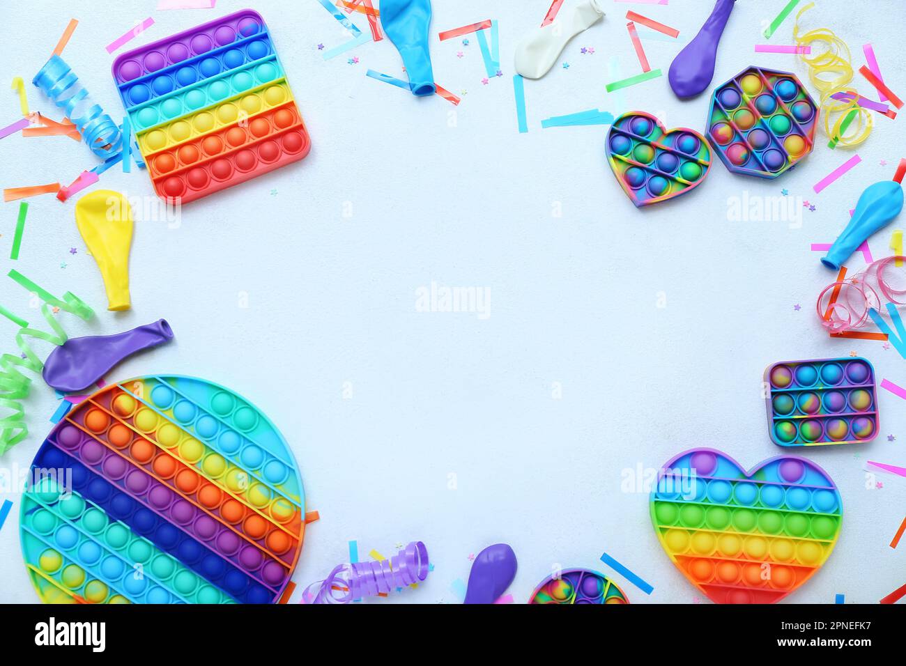 Frame made of pop it toys, balloons and confetti on white background ...