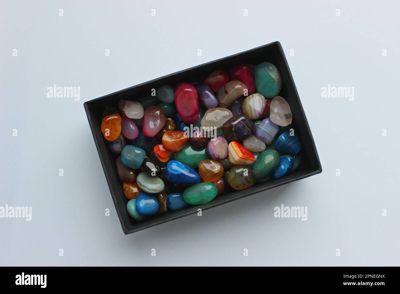 Bunch of raw semi-precious colored quartz stones in a black box top ...
