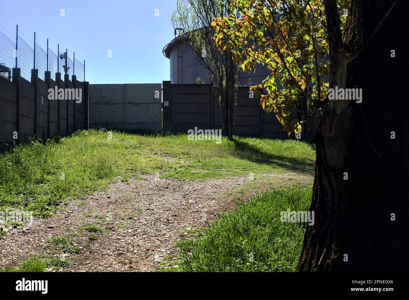 Path on an embankment next to a boundary wall of an industrial complex ...