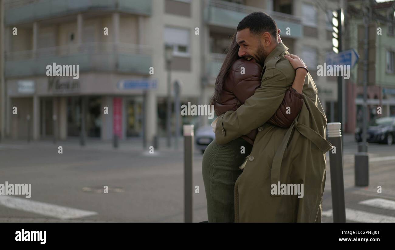 Two happy people embracing each other outside in city street. A joyful ...
