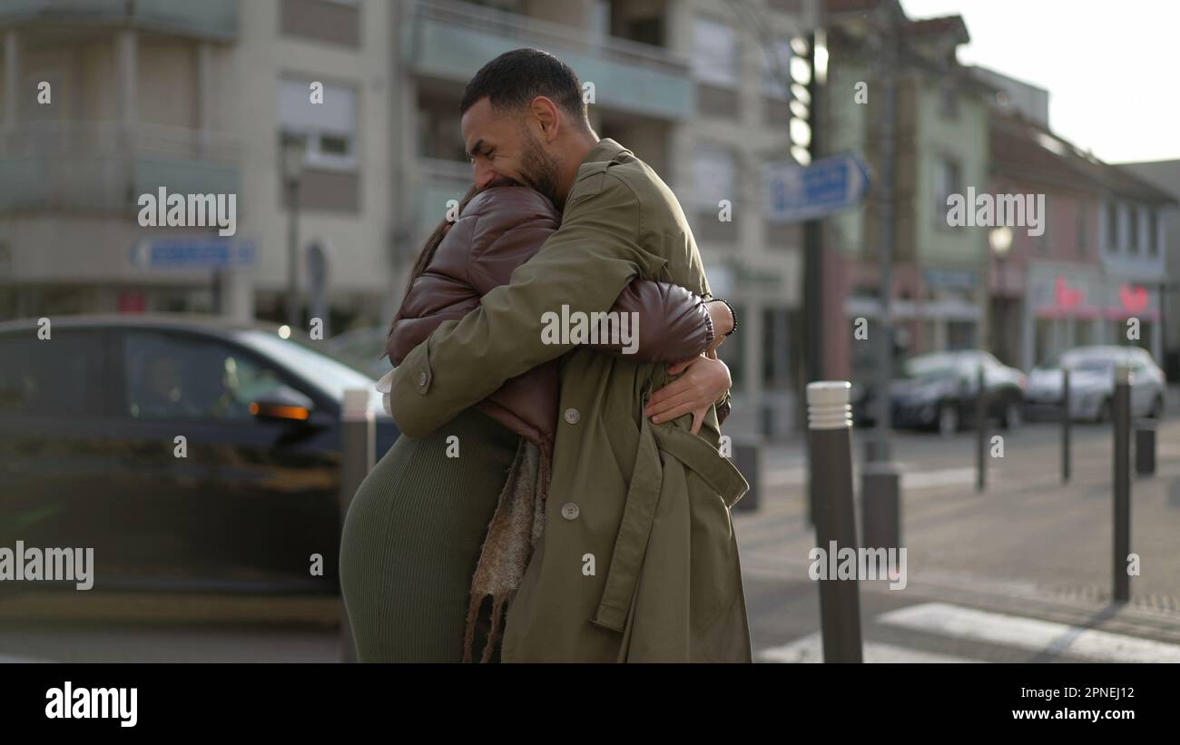 Two happy people embracing each other outside in city street. A joyful ...