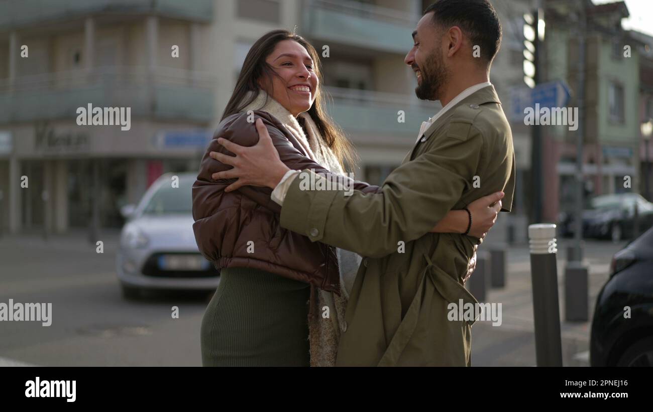 Two happy people embracing each other outside in city street. A joyful ...