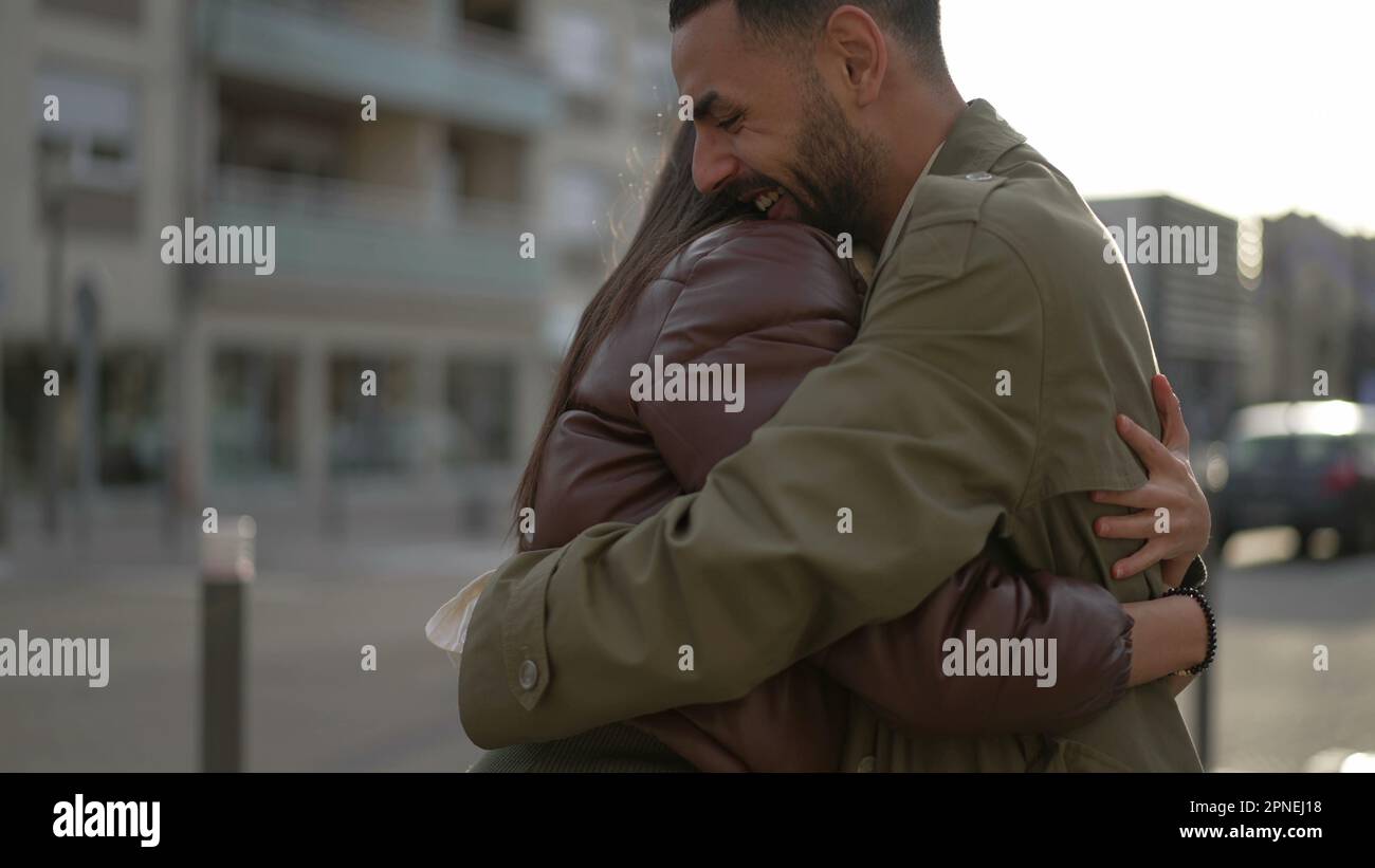 Two happy people embracing each other outside in city street. A joyful ...