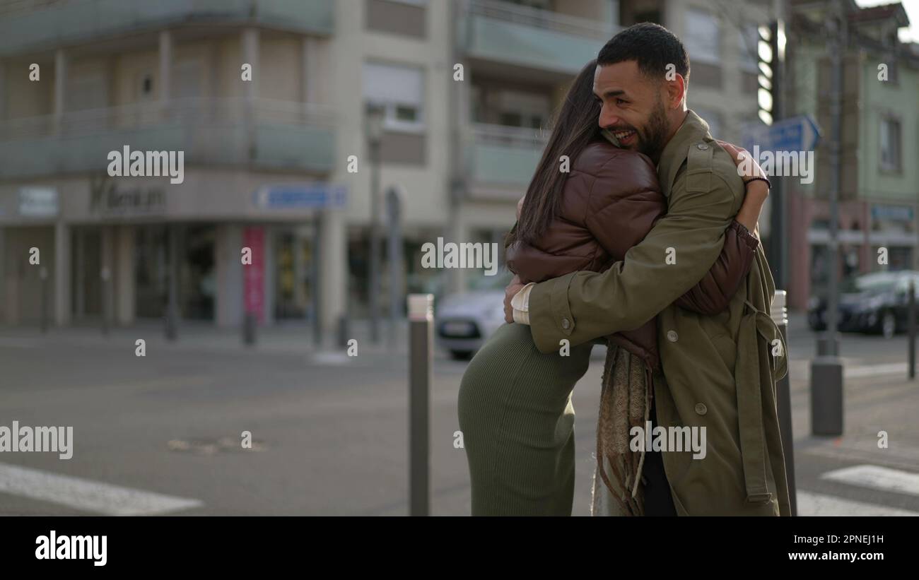 Two happy people embracing each other outside in city street. A joyful ...