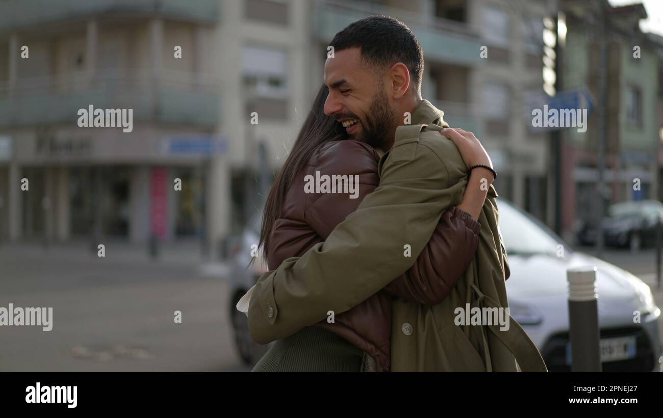 Two happy people embracing each other outside in city street. A joyful ...