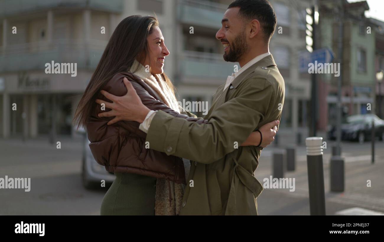 Two happy people embracing each other outside in city street. A joyful ...