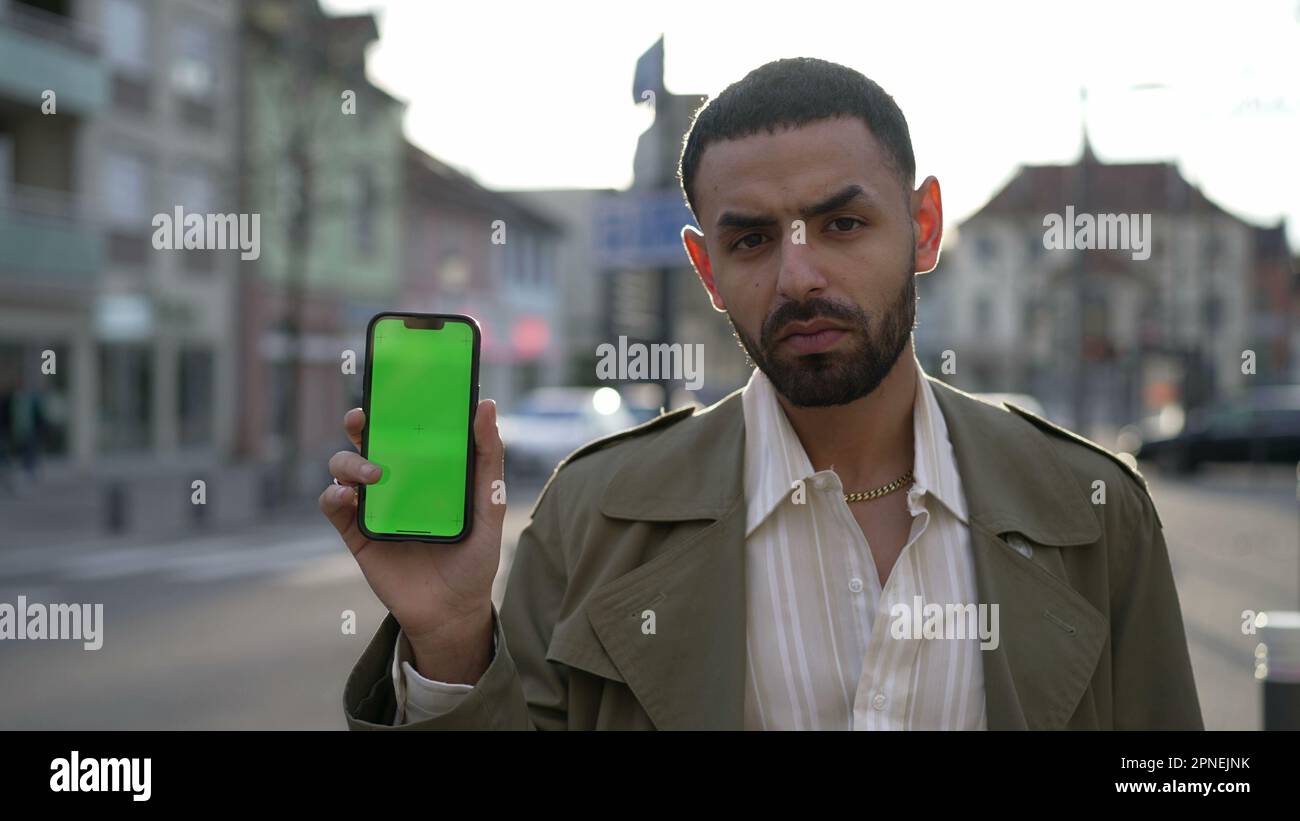 One serious Arab young man showing smartphone screen with chroma ...