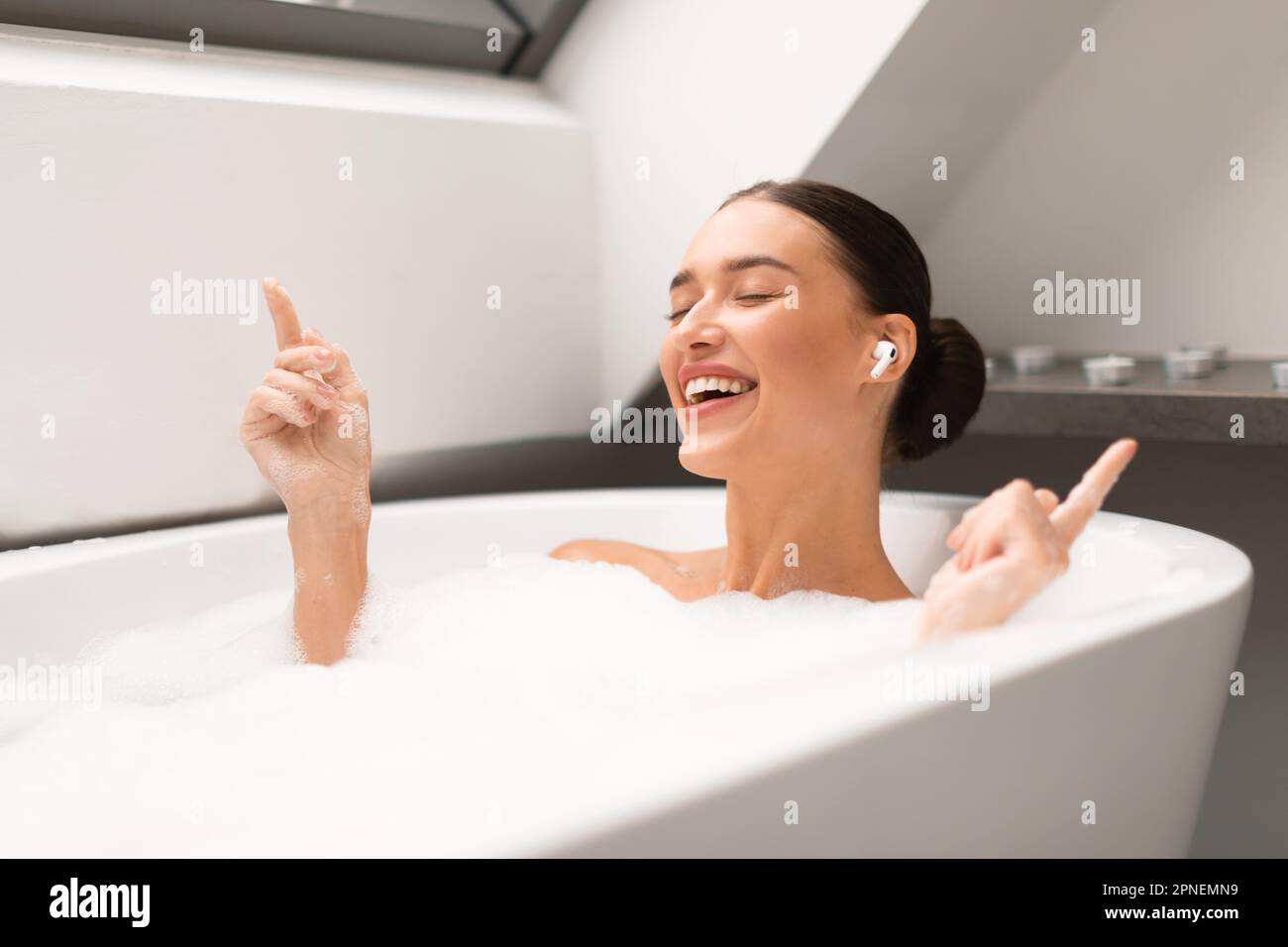 Relaxed female taking bath listening hi-res stock photography and ...