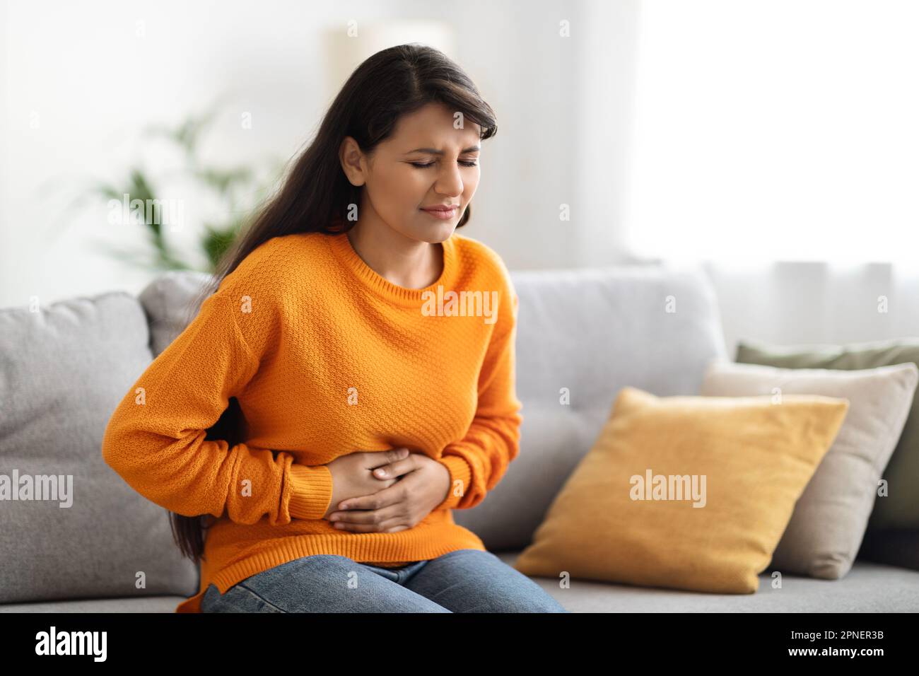 Concerned indian woman suffering from stomach-ache at home Stock Photo ...