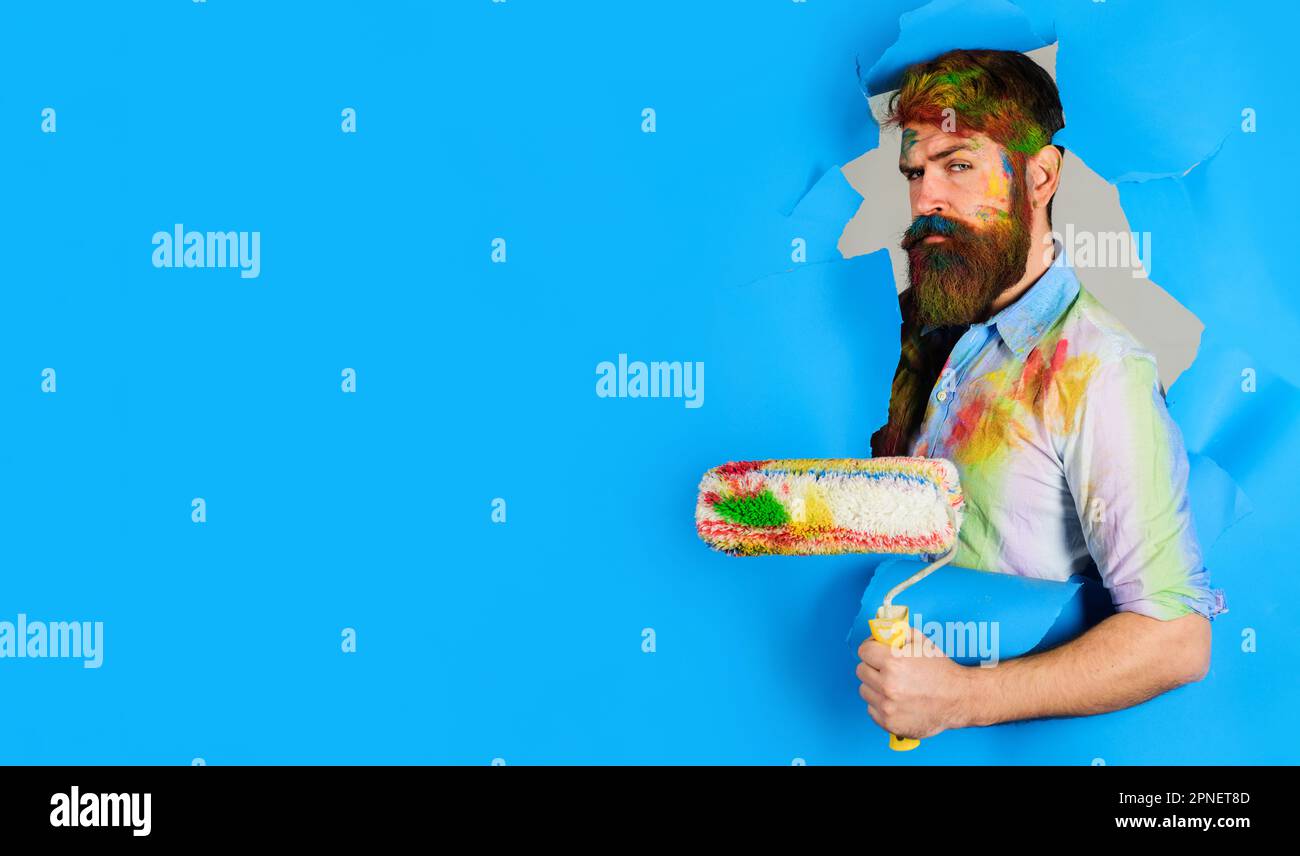 Painter man. Bearded painter with painting roller looking through hole ...