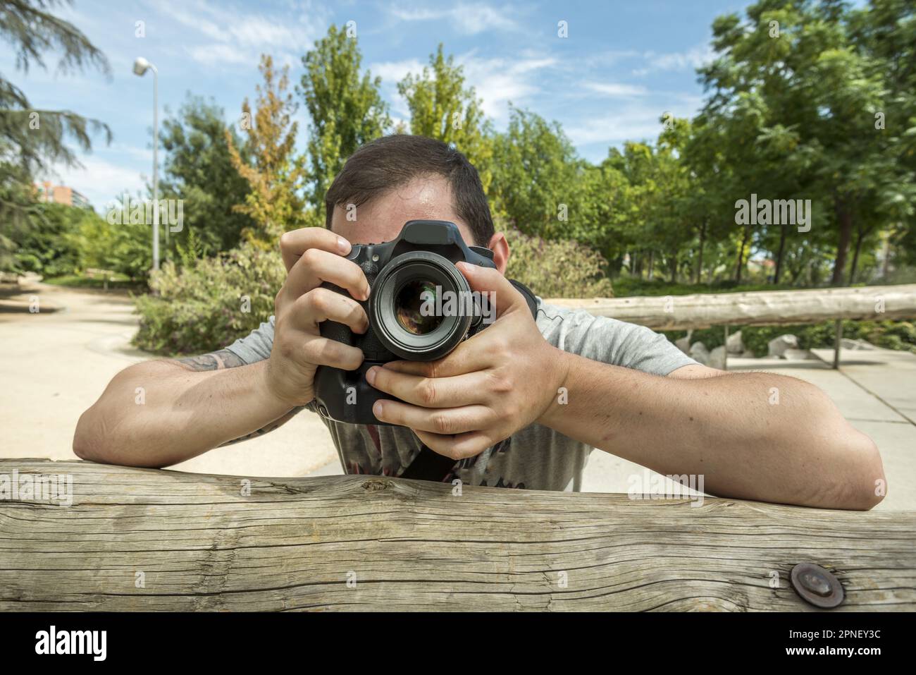 A photographer leaning on a wooden log making a tripod with his arms ...