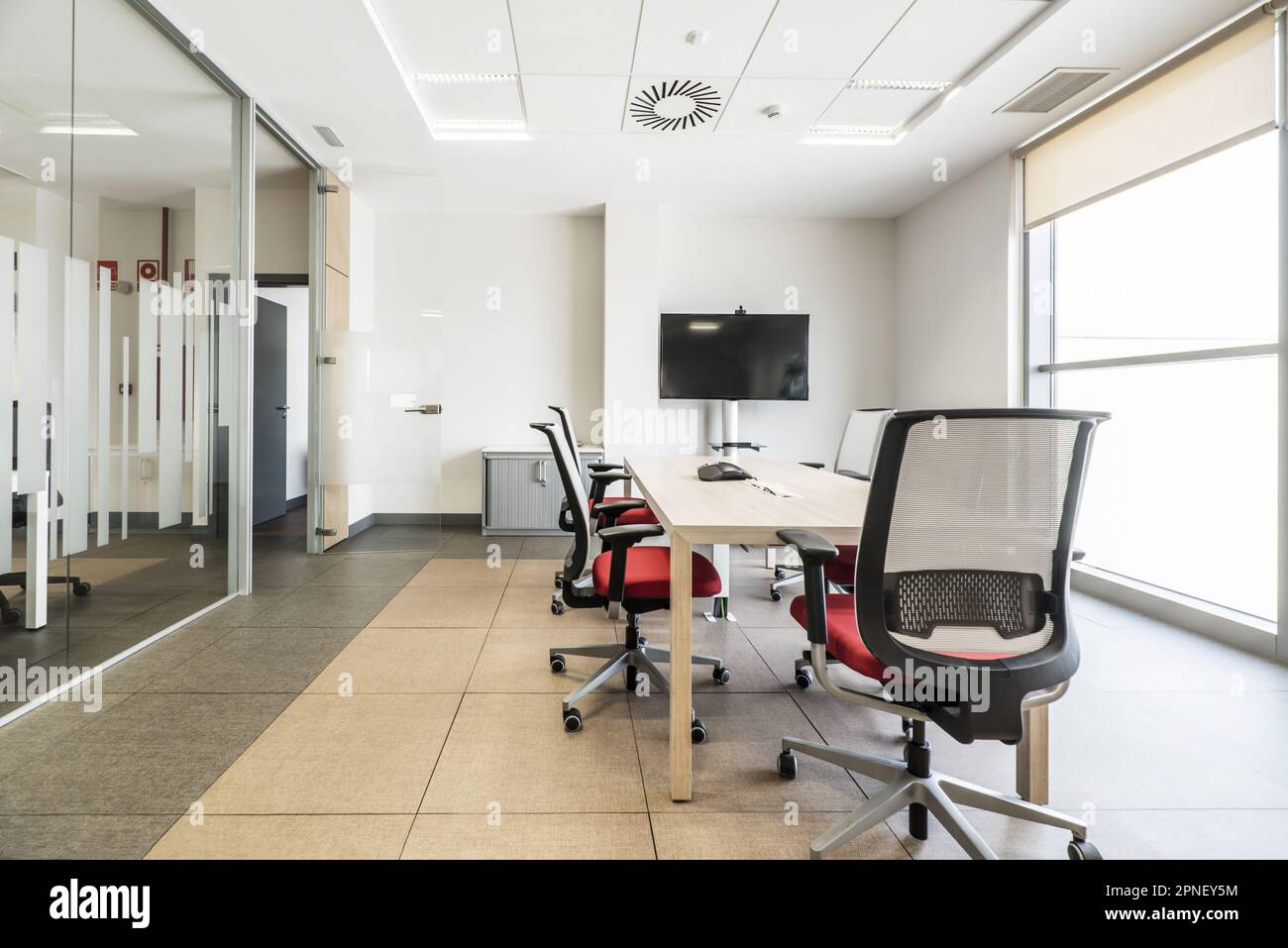A spacious office with glass partitions with several swivel chairs with ...