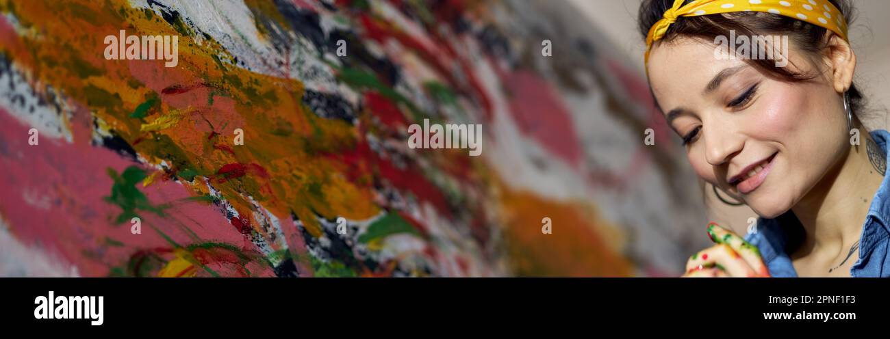 Relaxed young woman painter creating a large modern abstract oil ...