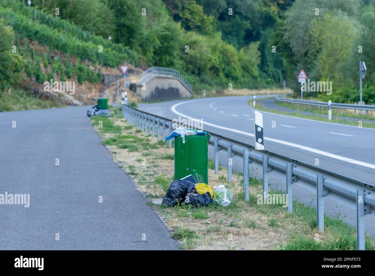 An overflowing rubbish bin at the roadside shows problems with disposal ...