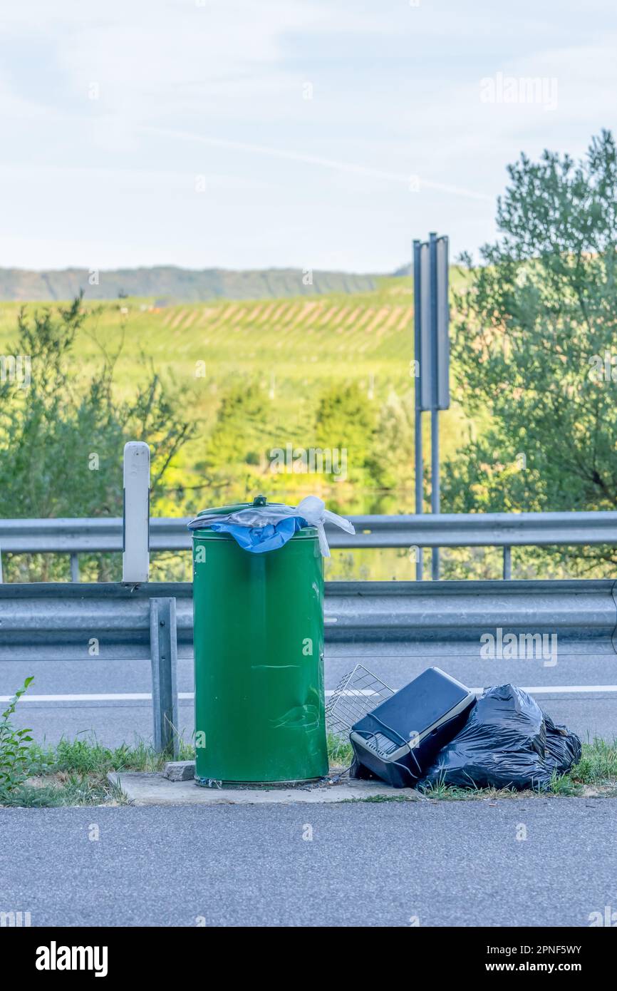 An overflowing rubbish bin at the roadside shows problems with disposal ...