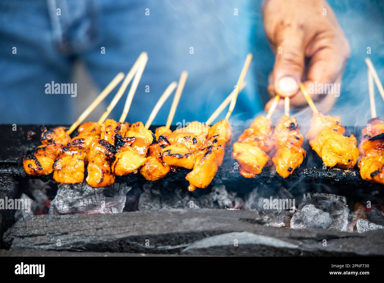 Closeup of chicken satay being barbecue with traditional pit and fired ...