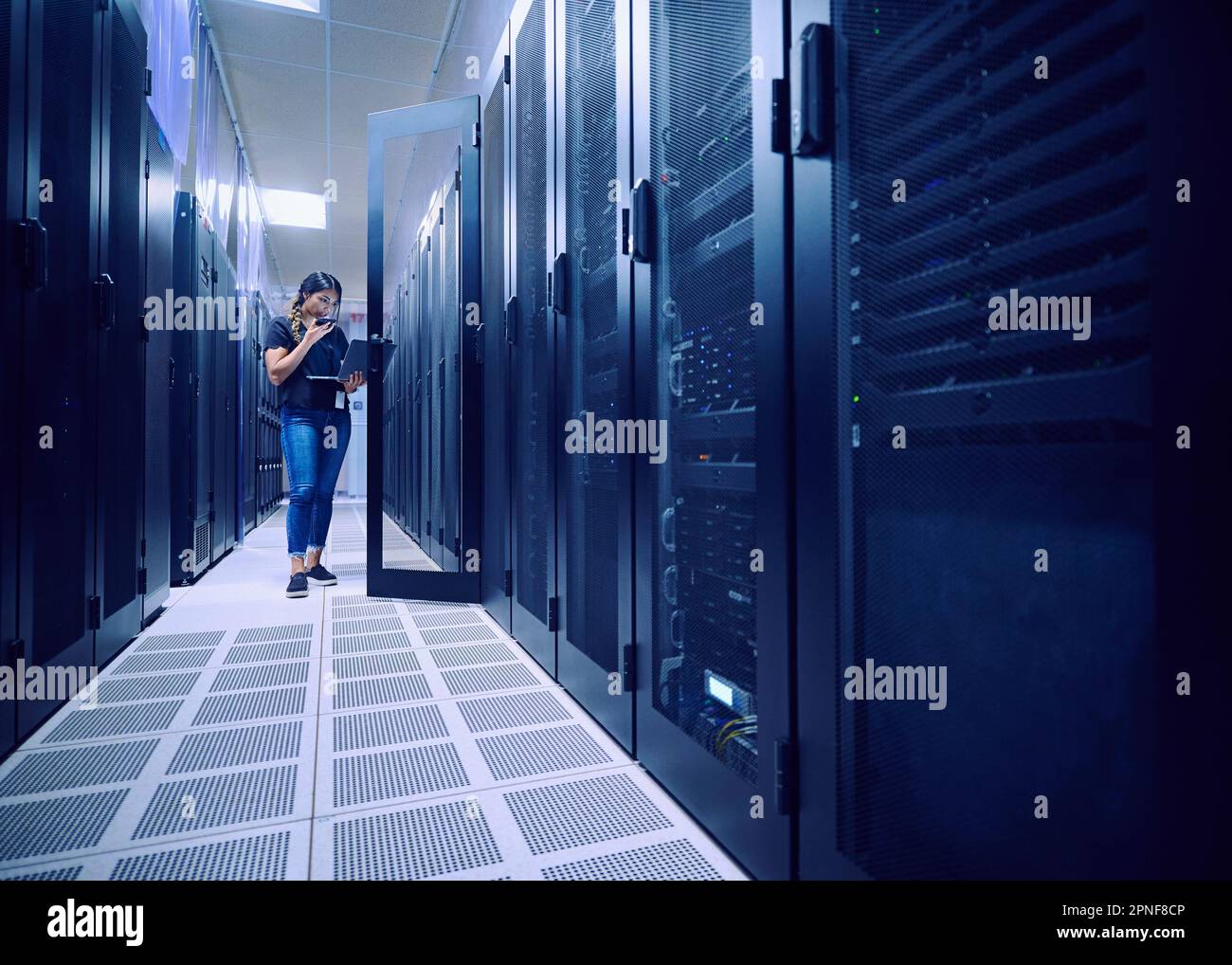 Female technician using laptop and phone in server room Stock Photo - Alamy