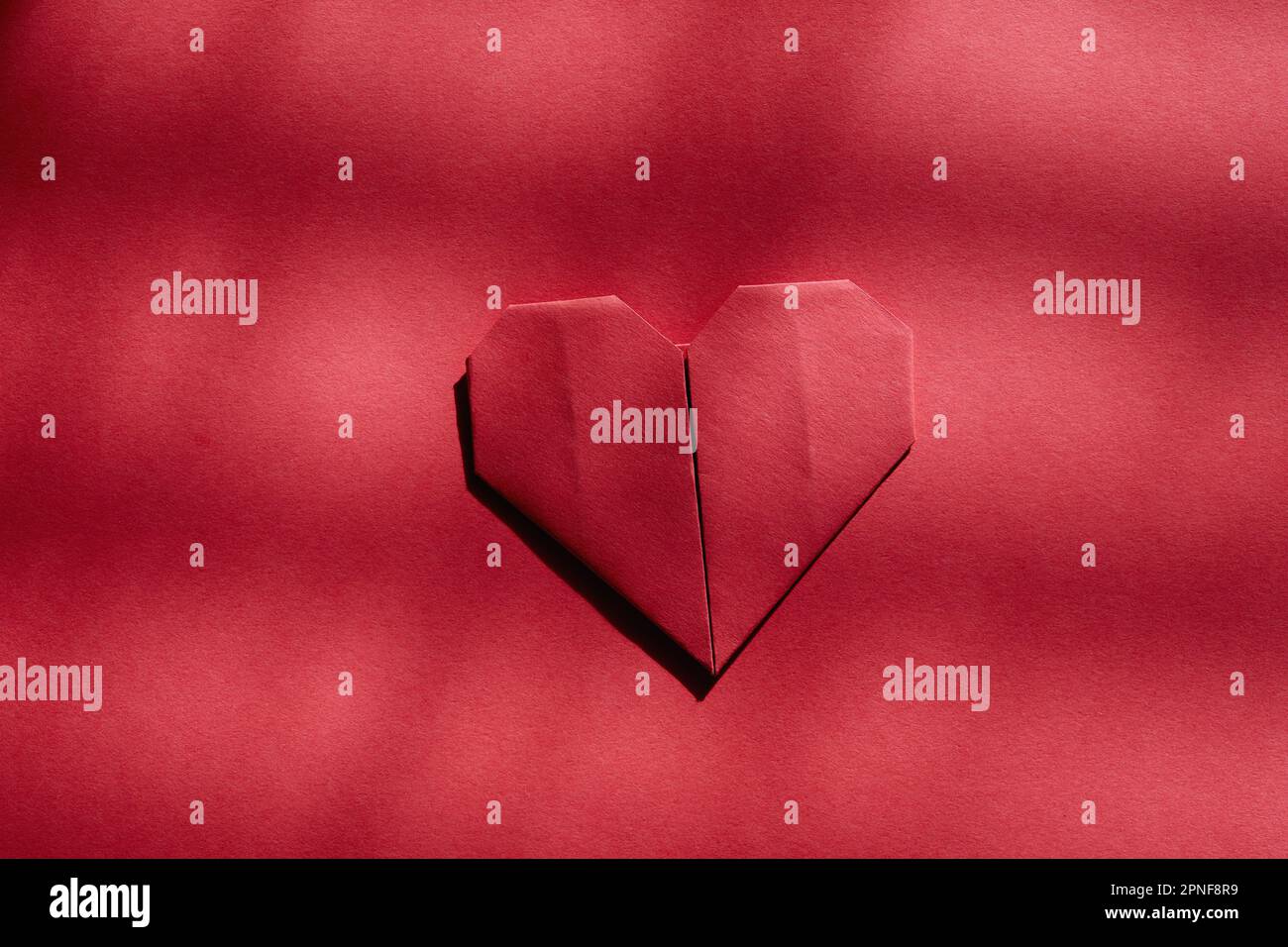 Red origami heart on red background Stock Photo - Alamy